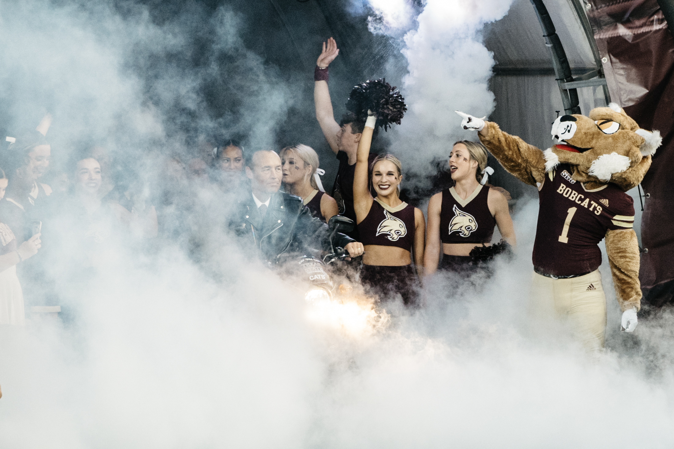 Standing beside TXST cheerleaders and President Damphousse, who sits on ...