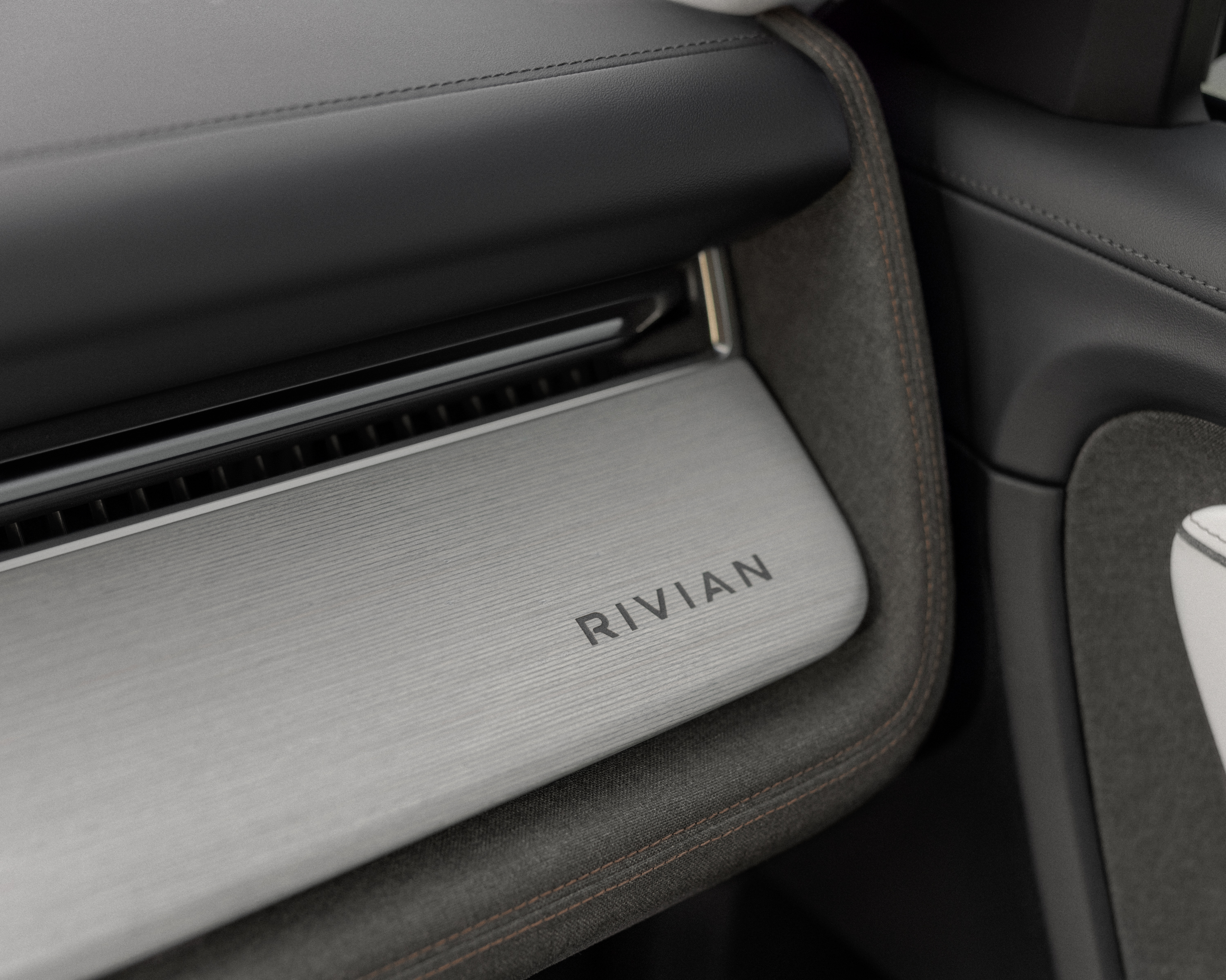 Close-up of the Rivian dashboard featuring a silver panel with the ...