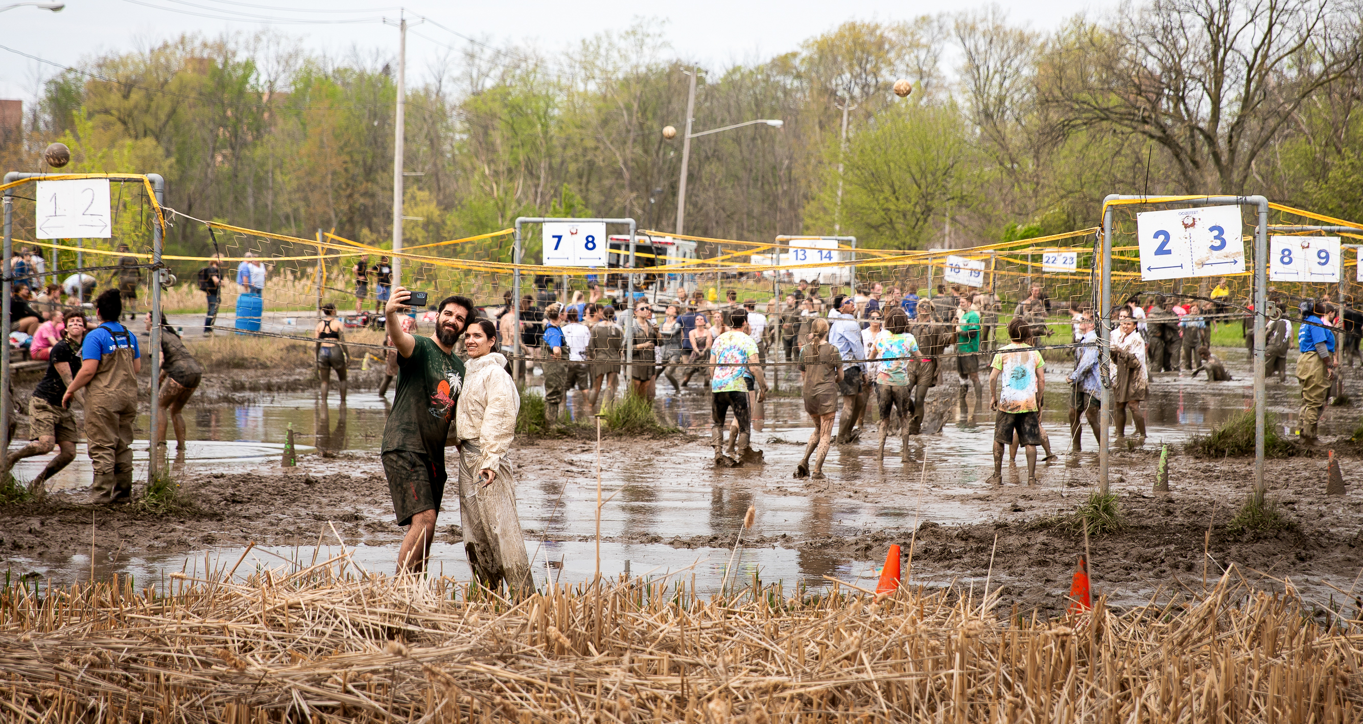 Two people pose for a selfie photo at the edge of the collection of mud ...