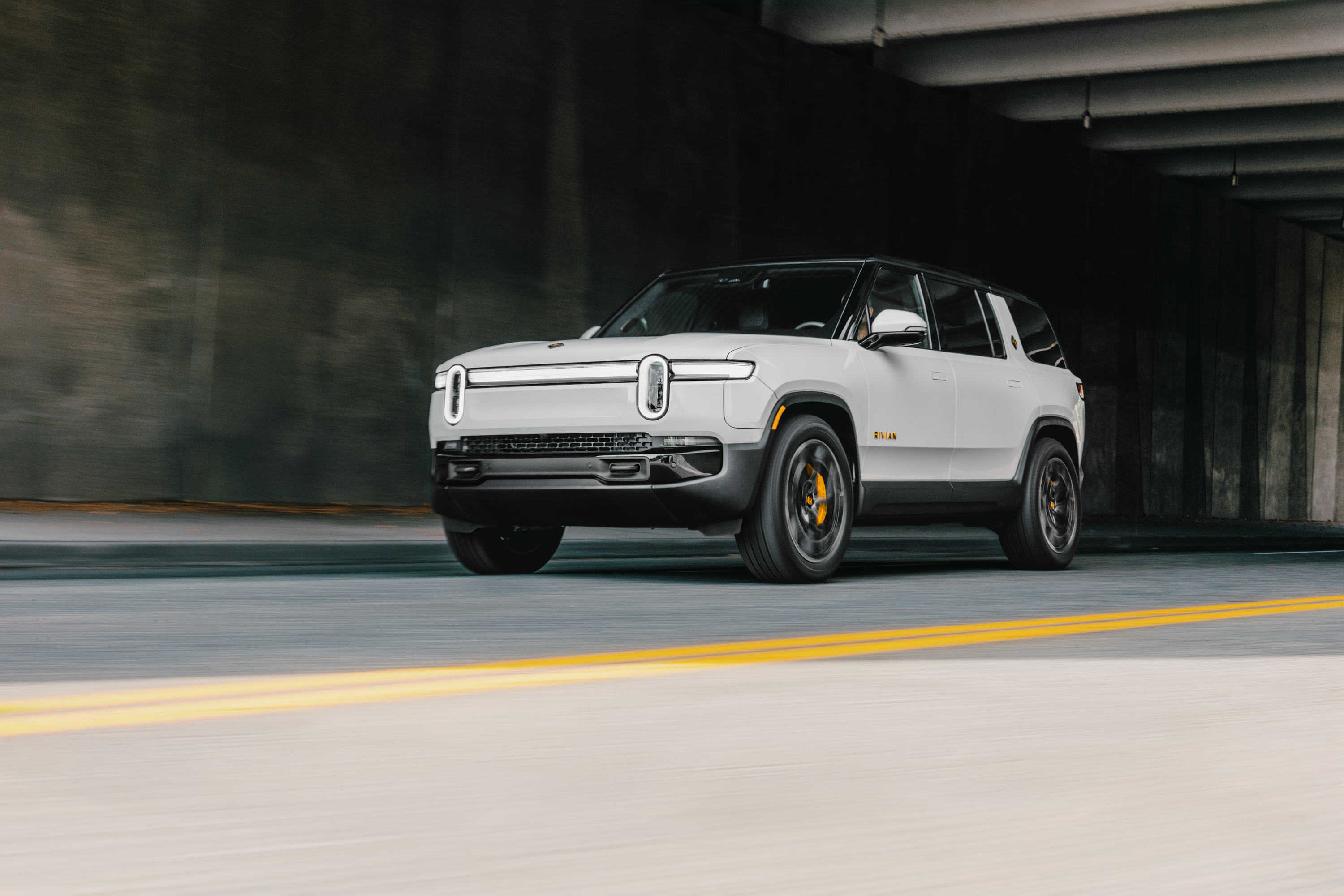 Rivian SUV drives on a road through a concrete tunnel. The vehicle is ...