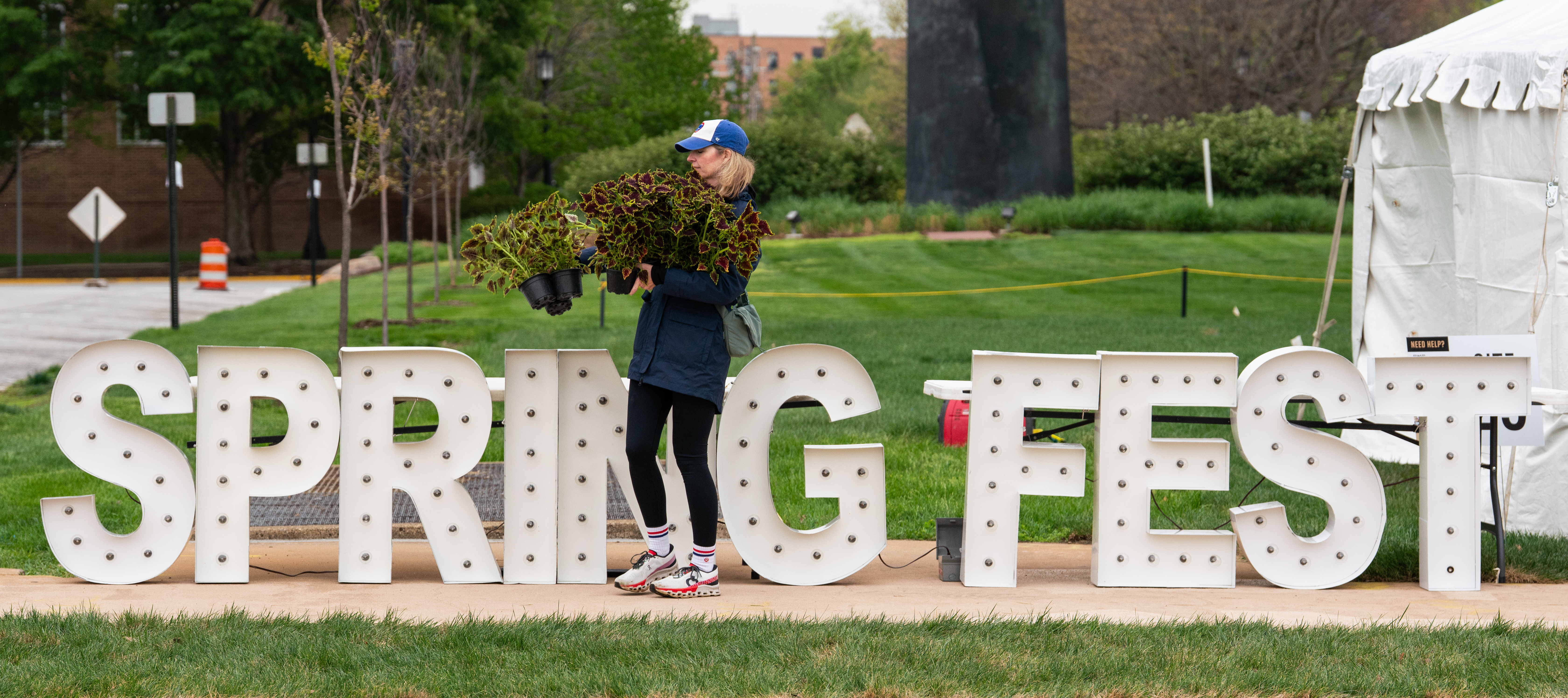 Woman carries potted plants past large