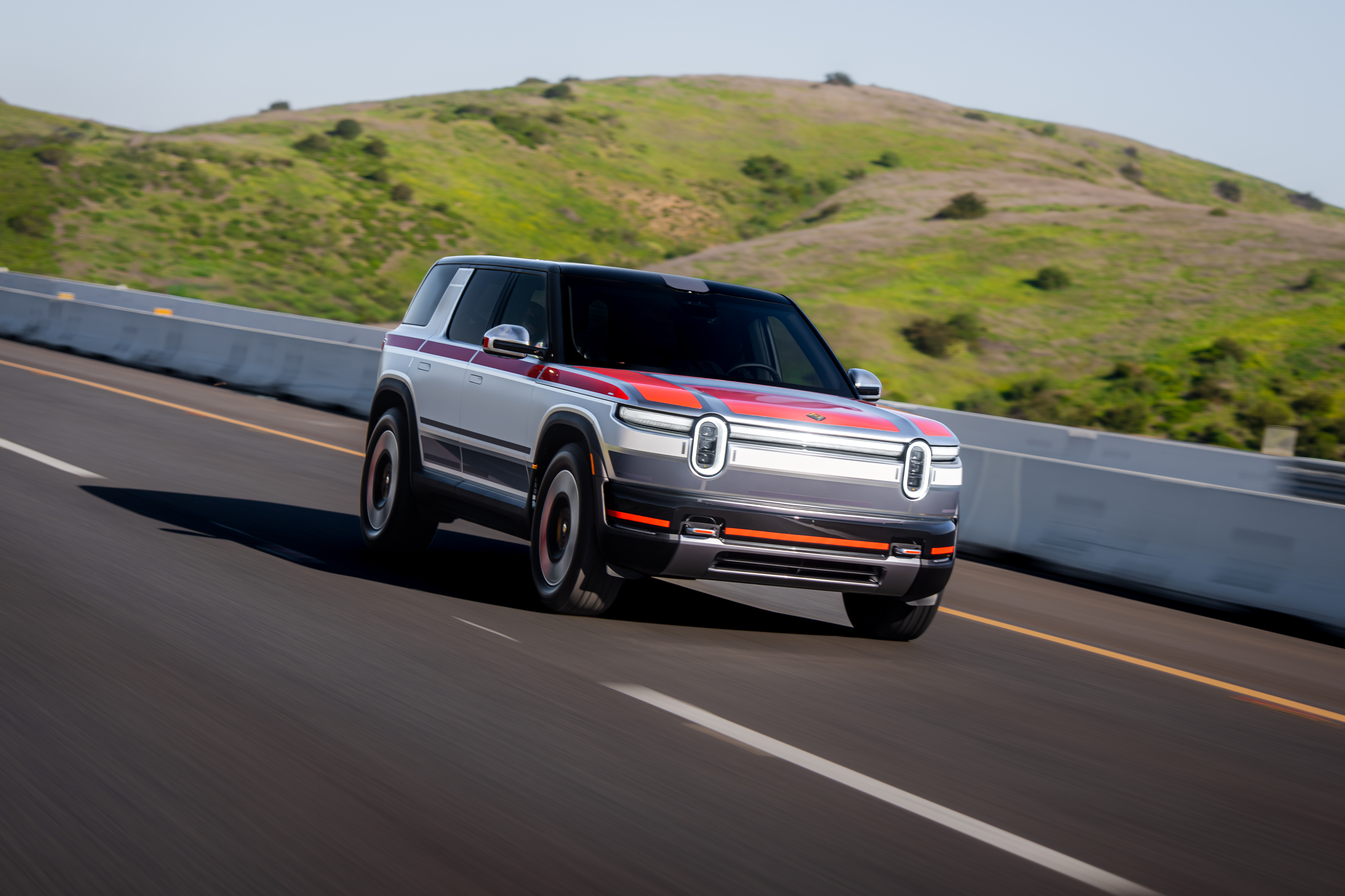 Rivian R2 prototype drives on highway, motion blur on road. The SUV has ...