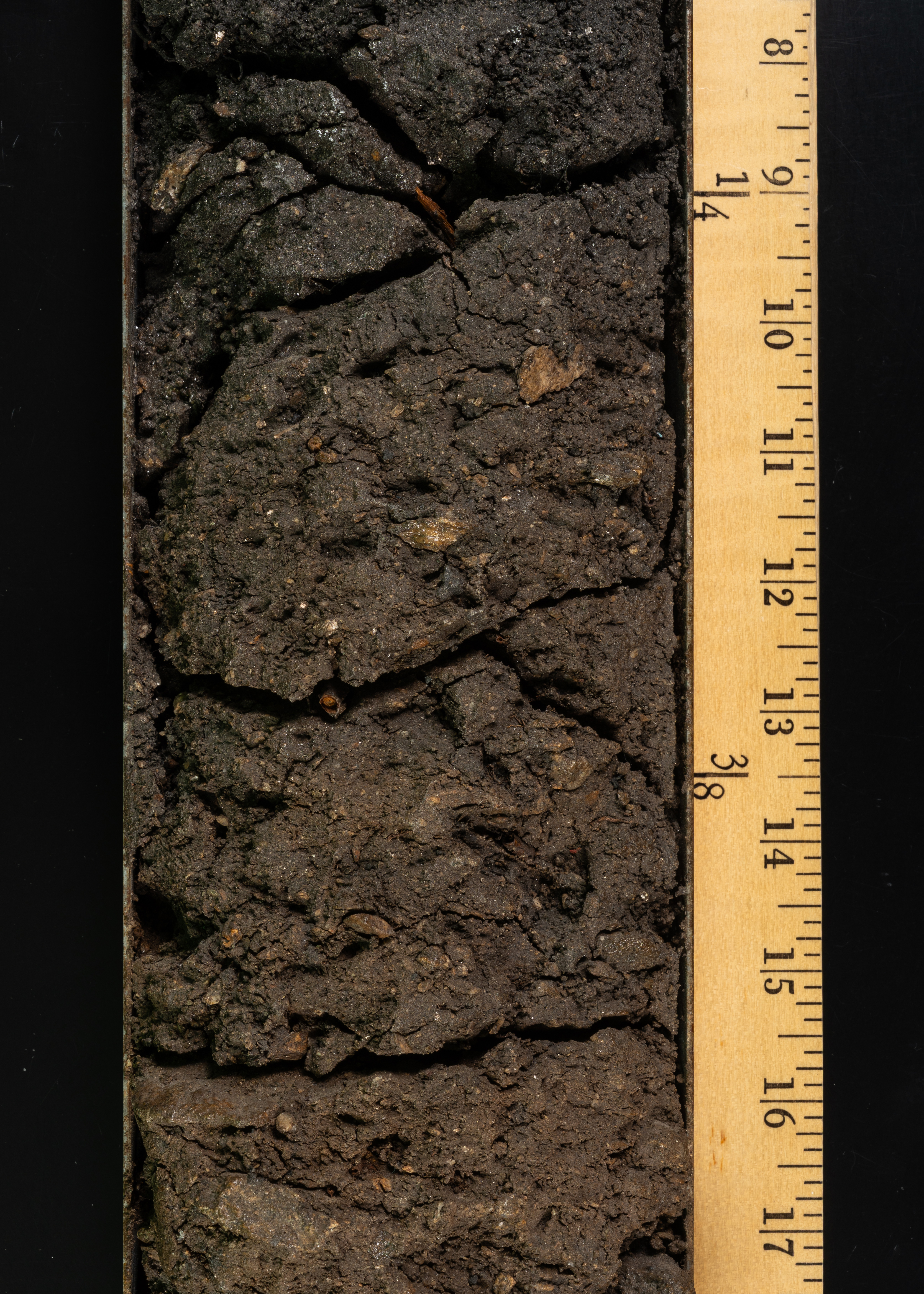 Soil sample shows dark, moist earth with small rocks, measured by a ...
