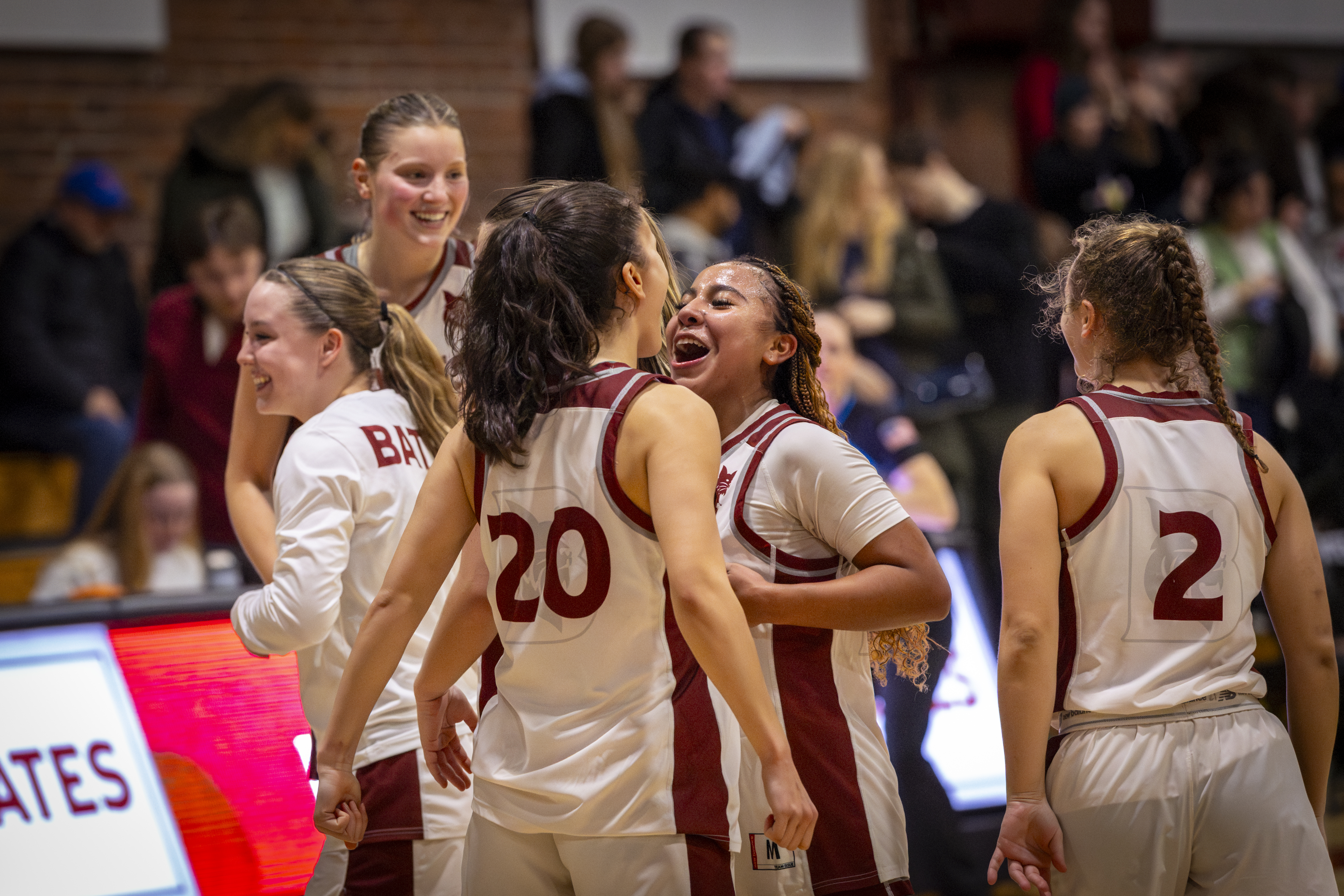 Bates women's basketball players celebrate a win, wearing white and ...