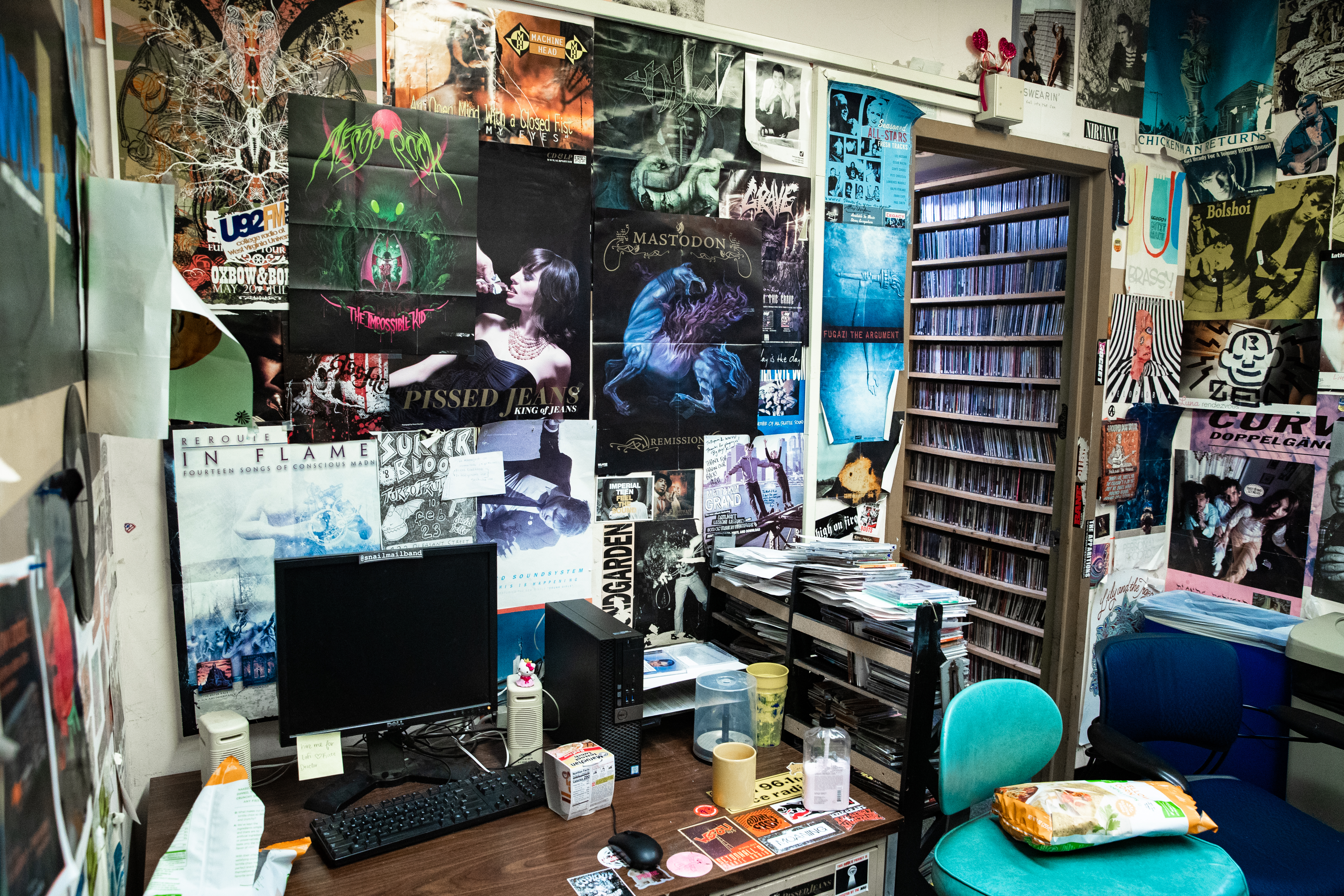 U92 radio station office: walls covered in band posters and stickers. A ...