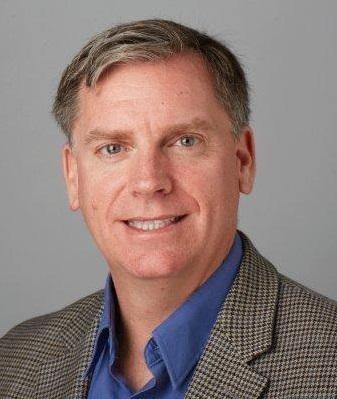 Portrait of a middle-aged man smiling, wearing a blue collared shirt ...