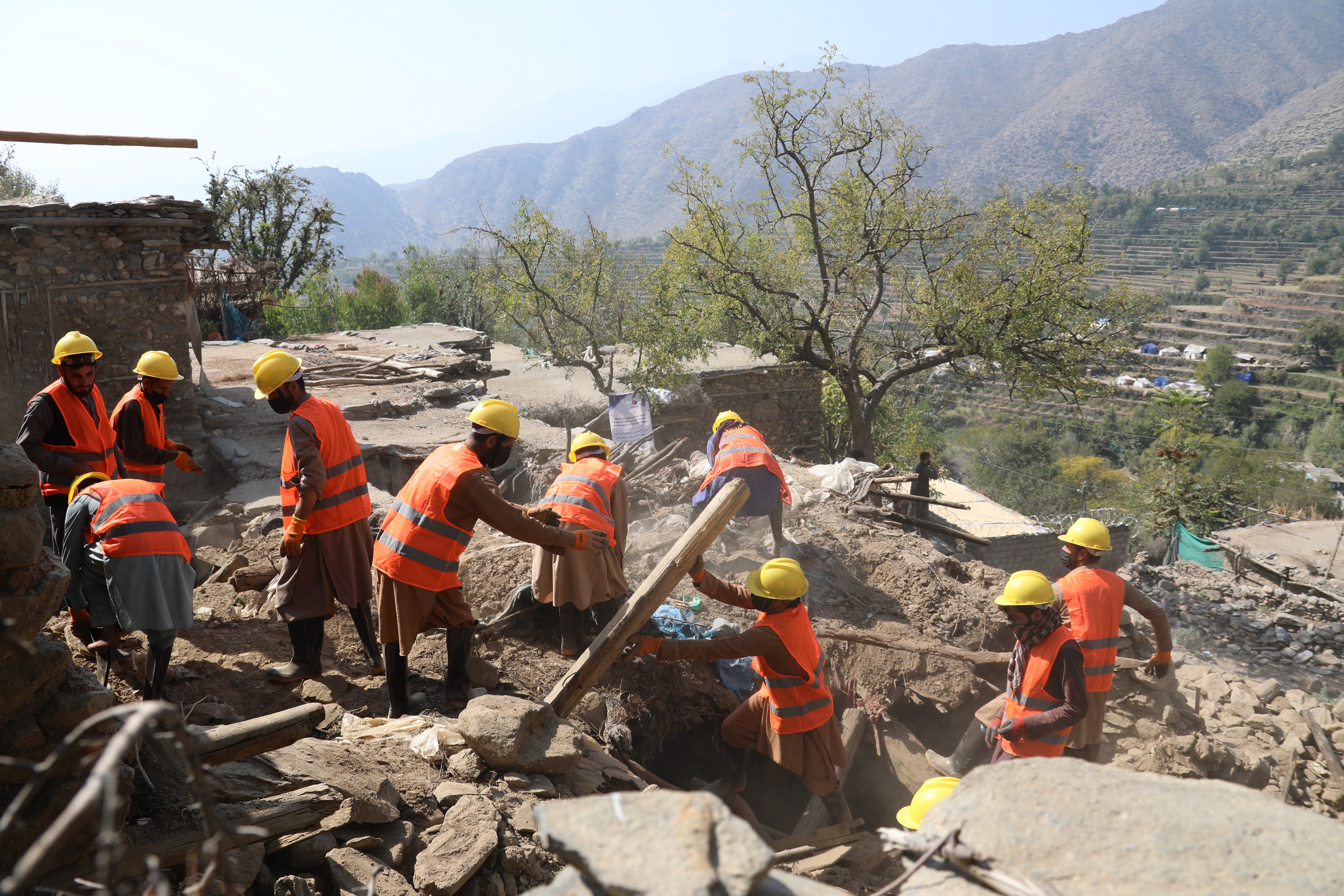 Rescue workers search through rubble in a mountainous region. The ...
