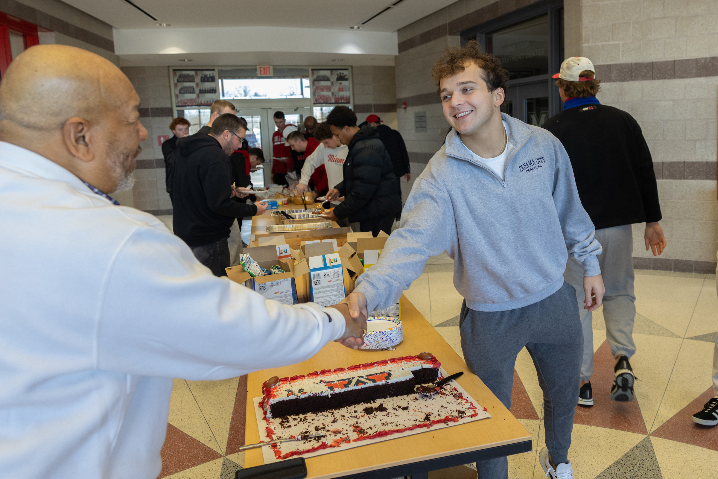 Person in white coat shakes hands with a smiling young man in a gray ...