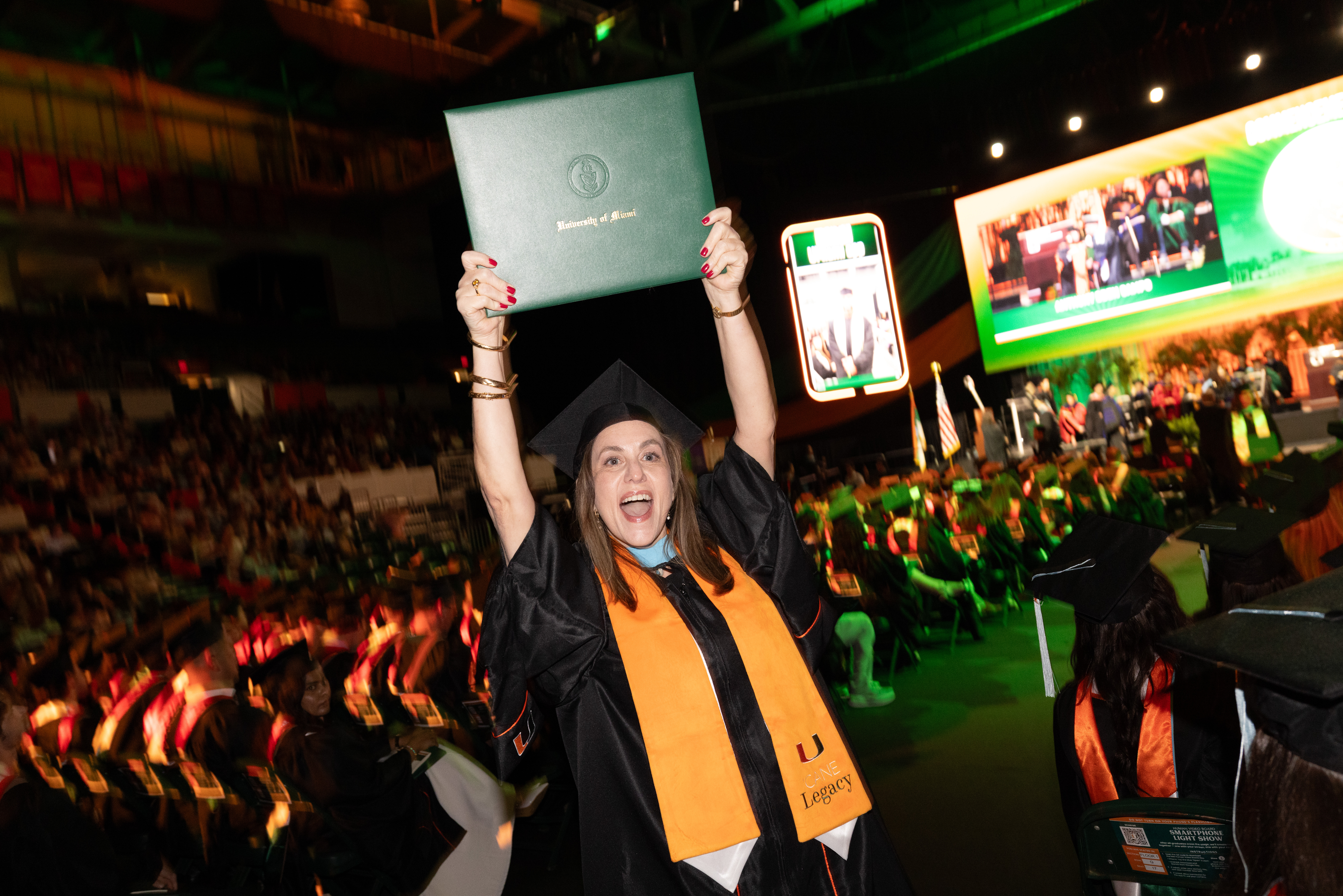 Graduate in cap and gown raises diploma overhead at University of Miami ...