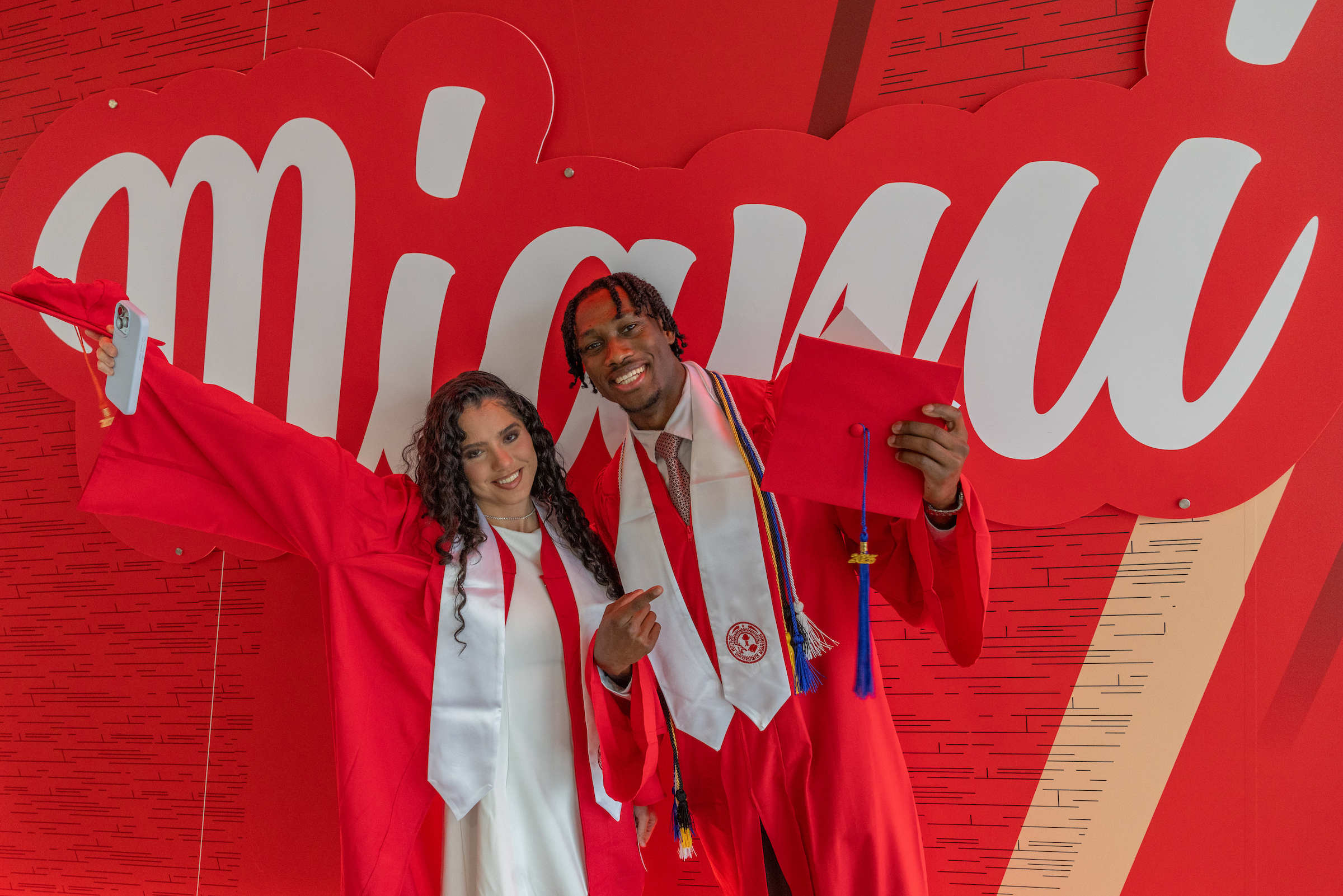 Two Miami University degree candidates pose for a photo at Millett Hall.