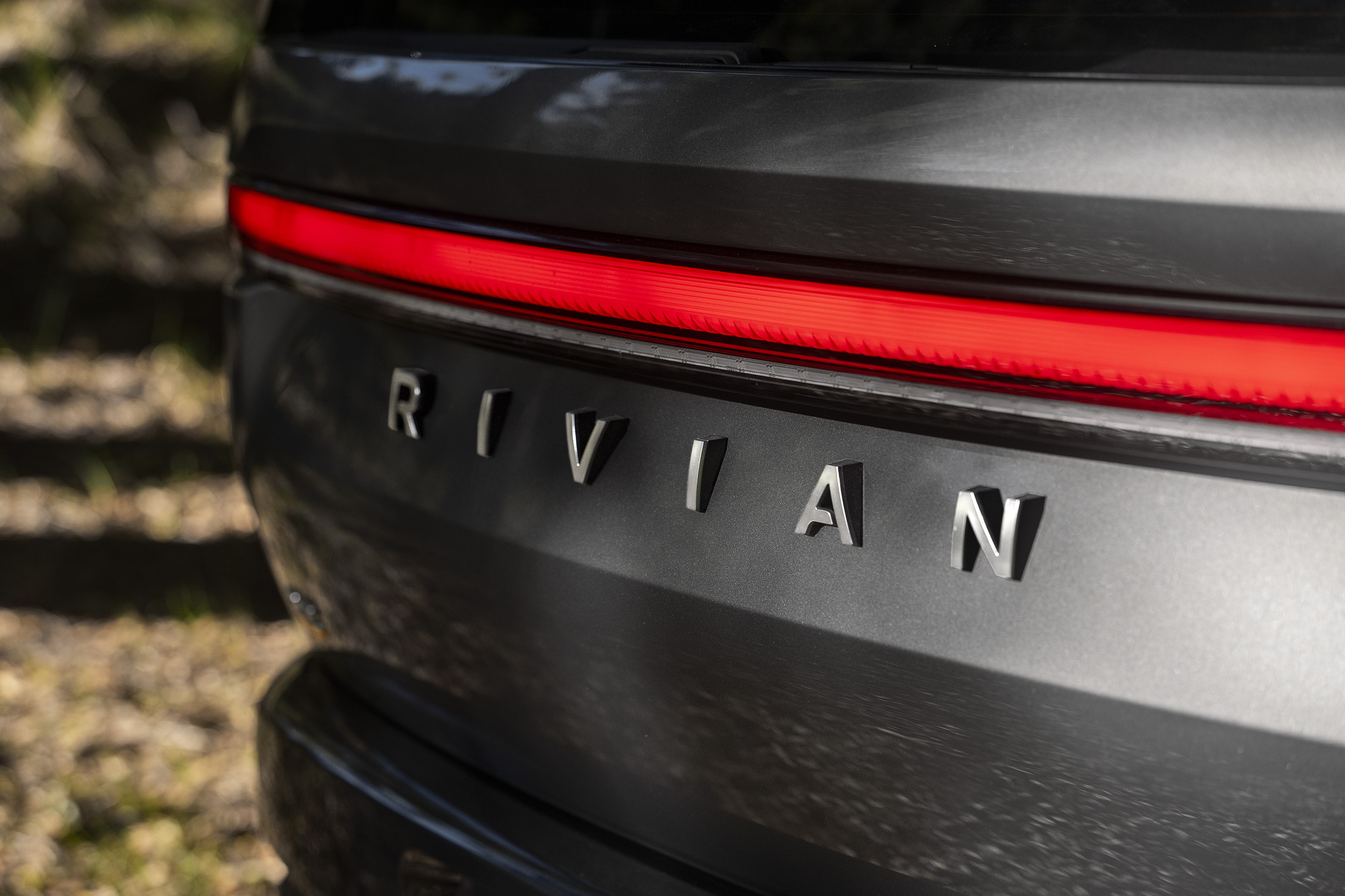 Close-up of the rear of a gray Rivian vehicle, illuminated red ...