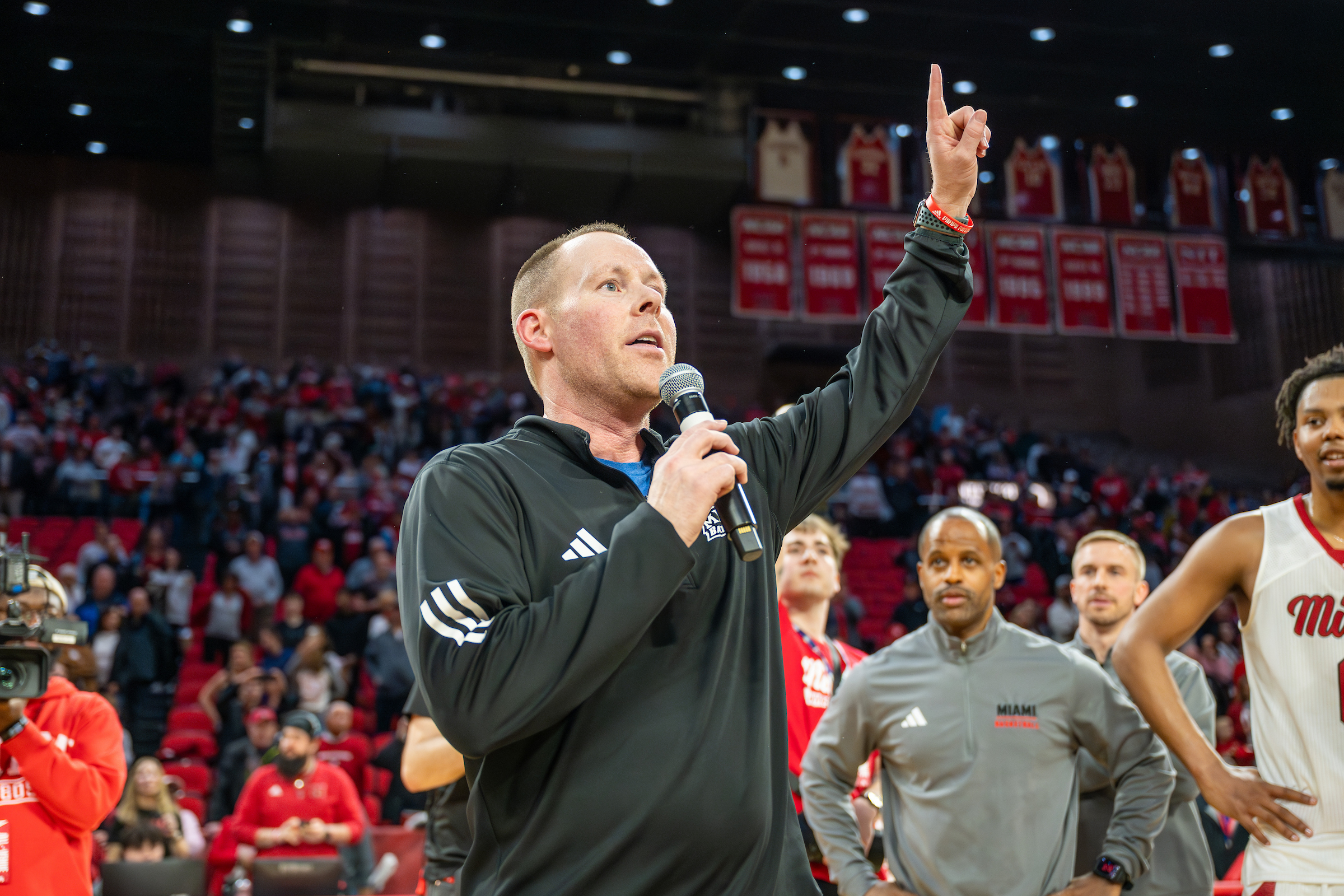 Miami D6026 Mens Basketball coach speaks into a microphone, raising his ...