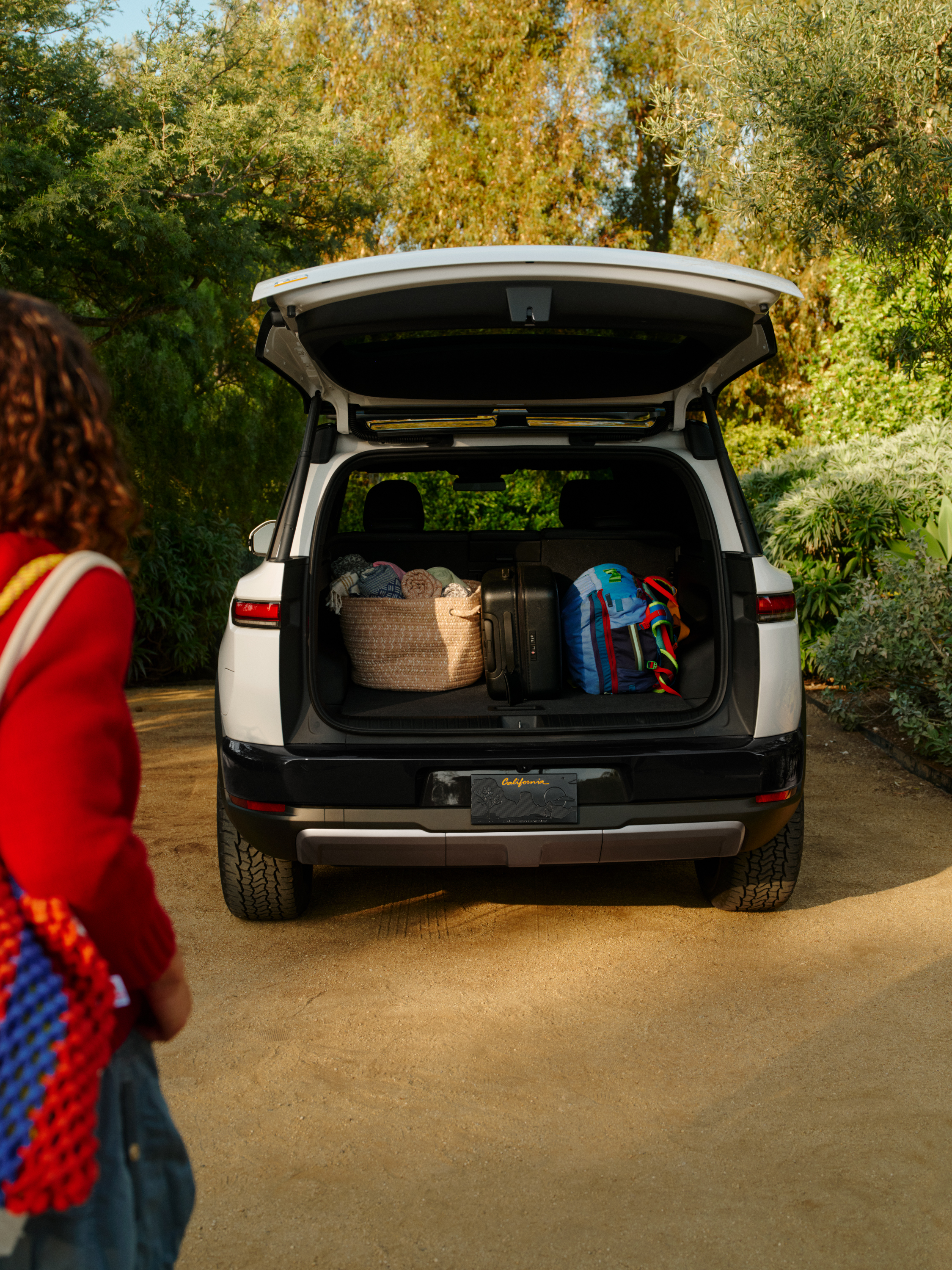 Rear view of a white R2 SUV with open trunk, packed with a suitcase ...