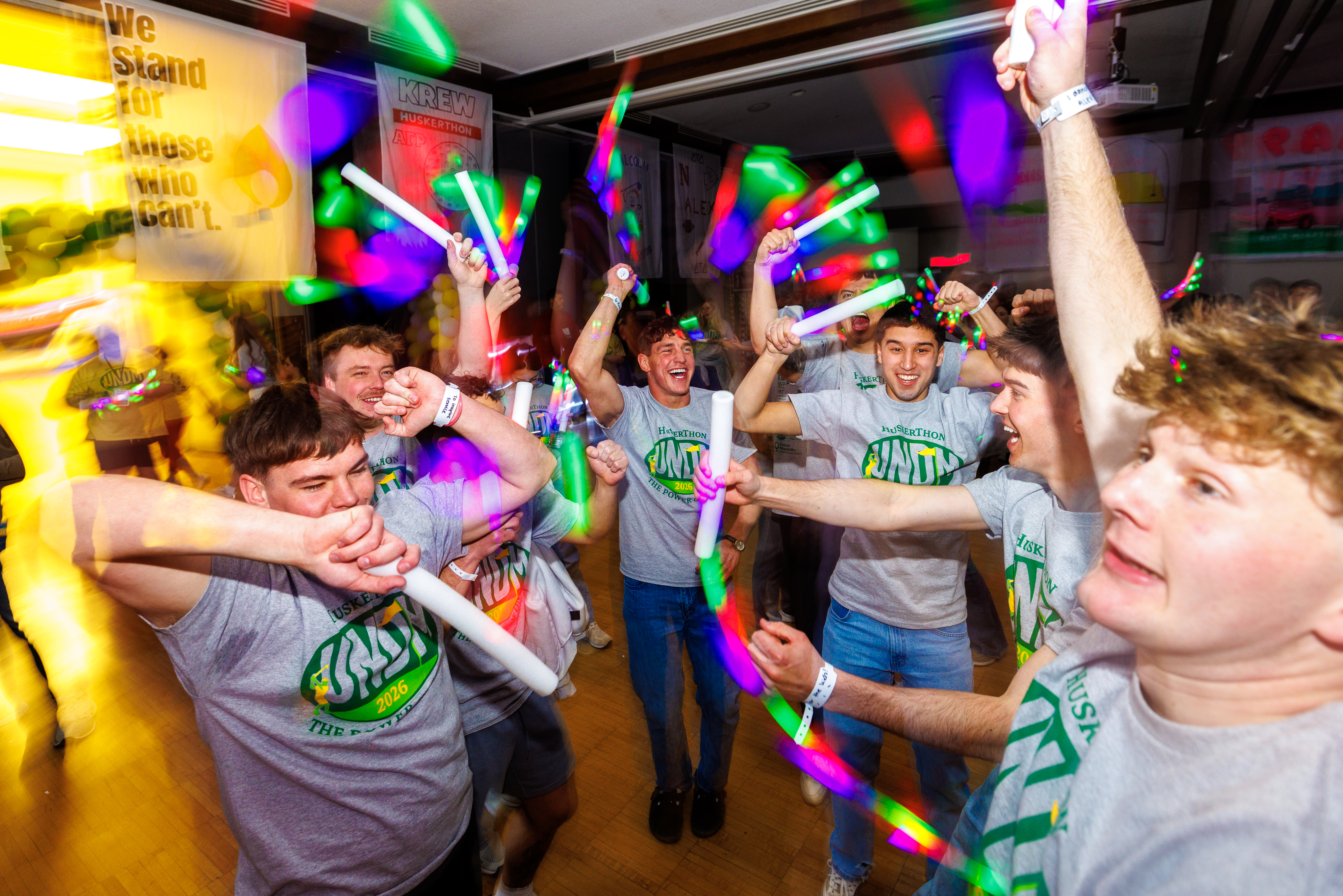Students dance at the UNL Dance Marathon rave, holding up glowing tubes ...