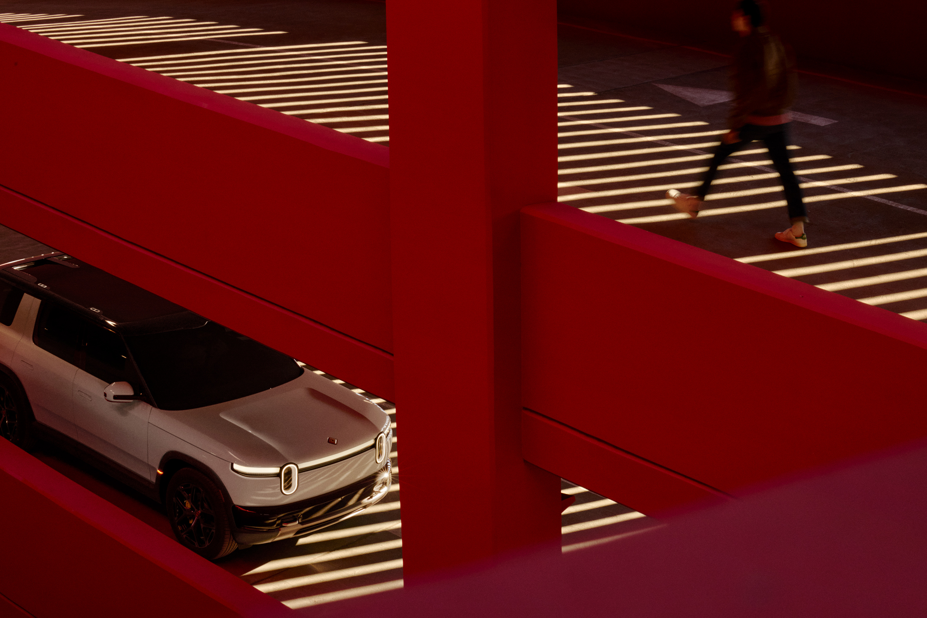 A white SUV sits in a parking garage while a person walks in the ...